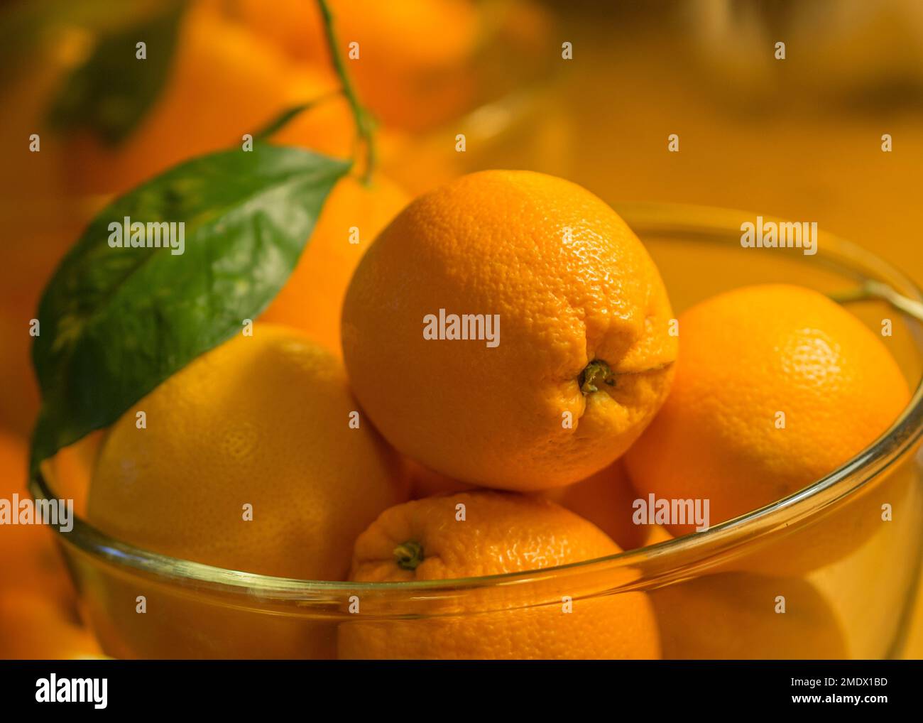 A closeup shot of fresh oranges placed in a transparent glass bowl ...