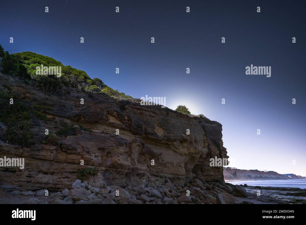 A scenic view of the sunlight shining brightly from behind a coastal ...