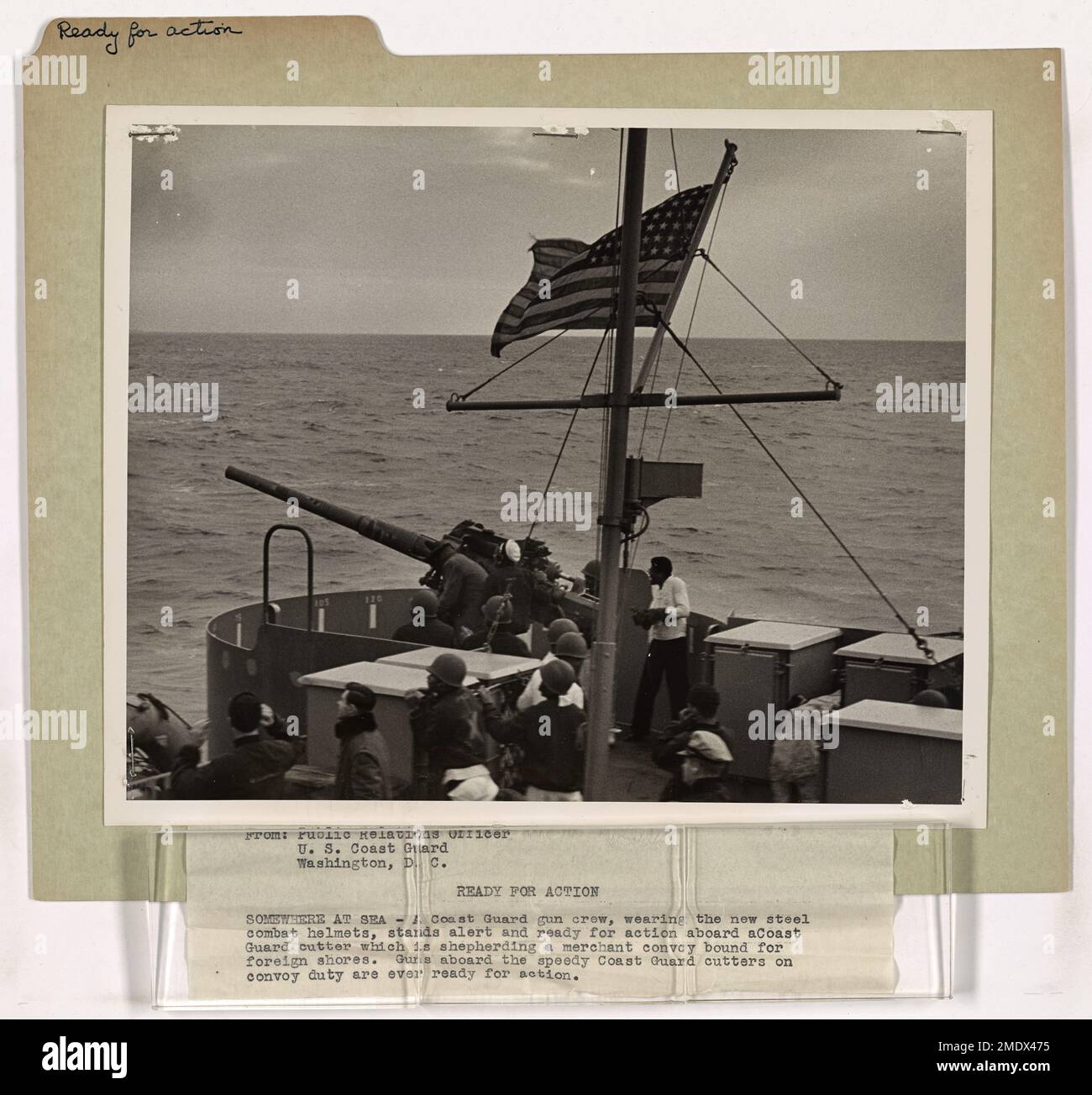 A Coast Guard gun crew, equipped with new steel combat helmets, stands ...