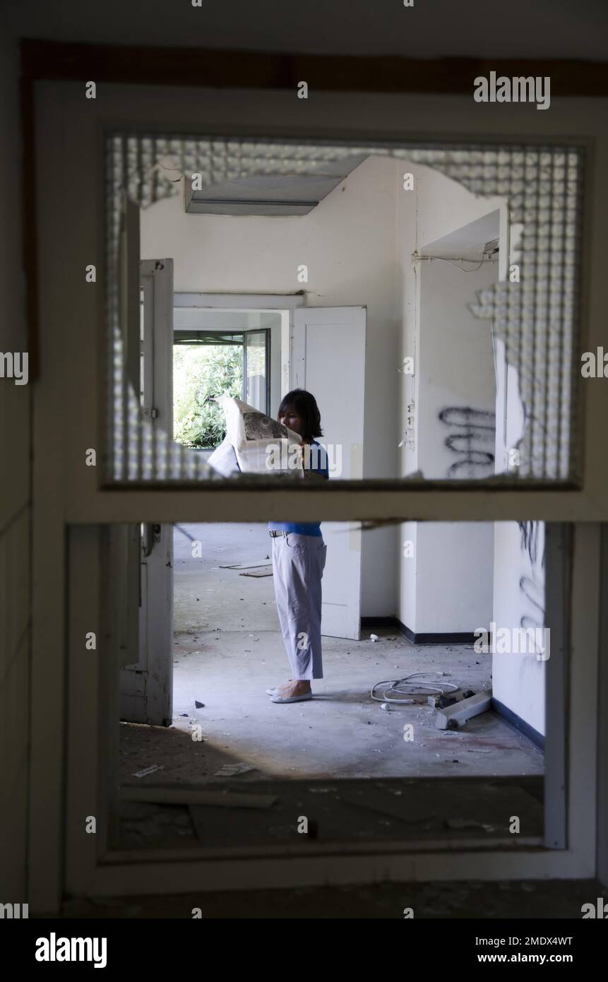Woman Standing Inside an Abandoned Building and Reading a Newspaper ...