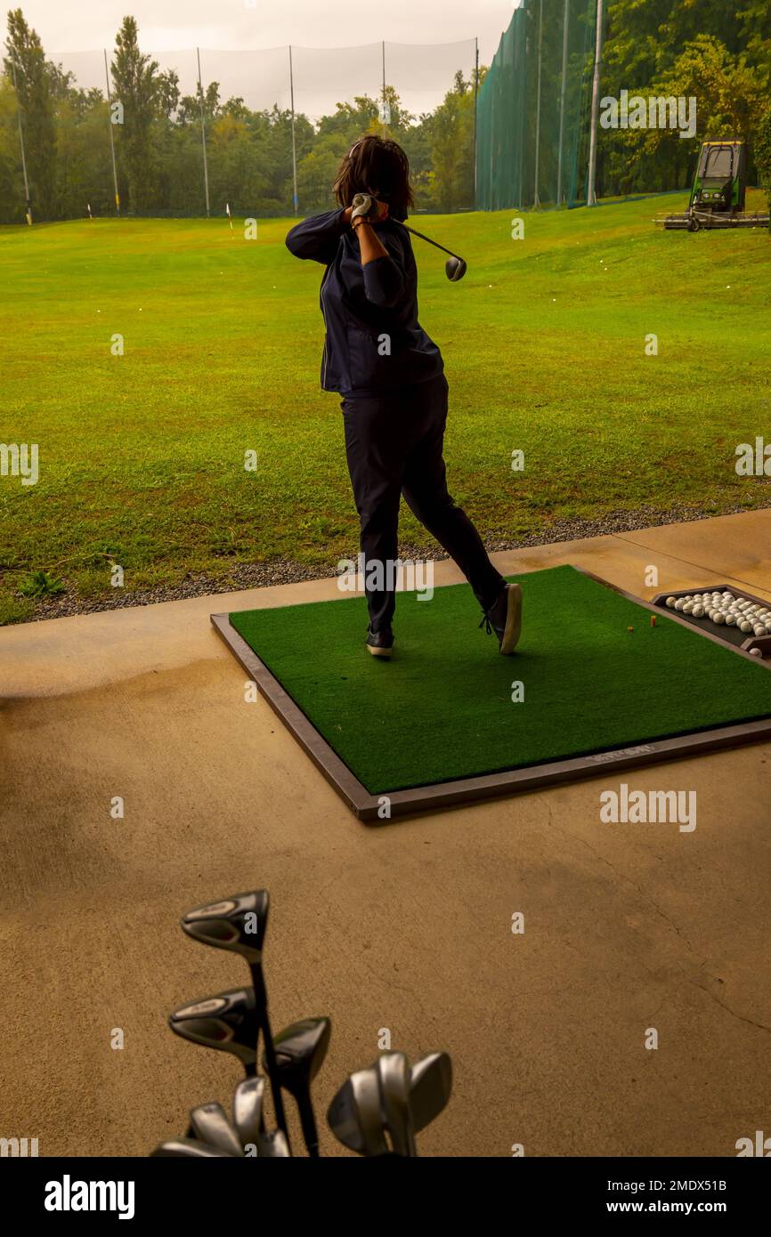 Golfer Training Her Golf Club Driver on Driving Range in a Rainy Day in ...