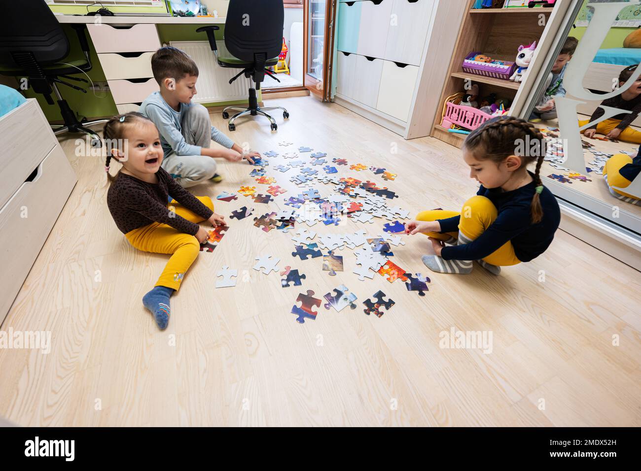 Children connecting jigsaw puzzle pieces in a kids room on floor at ...