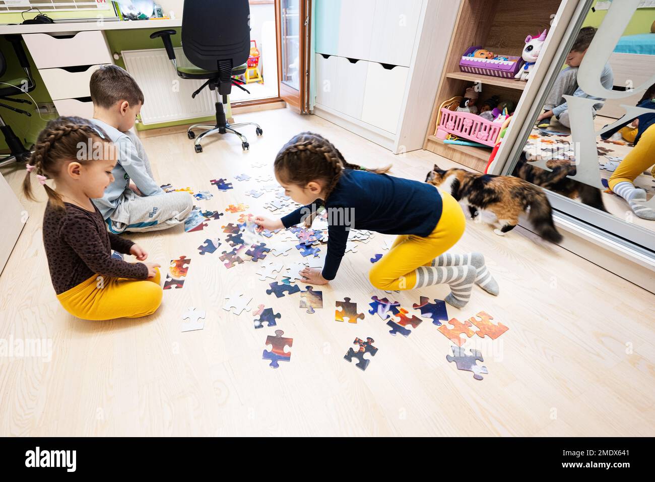 Children connecting jigsaw puzzle pieces in a kids room on floor at ...
