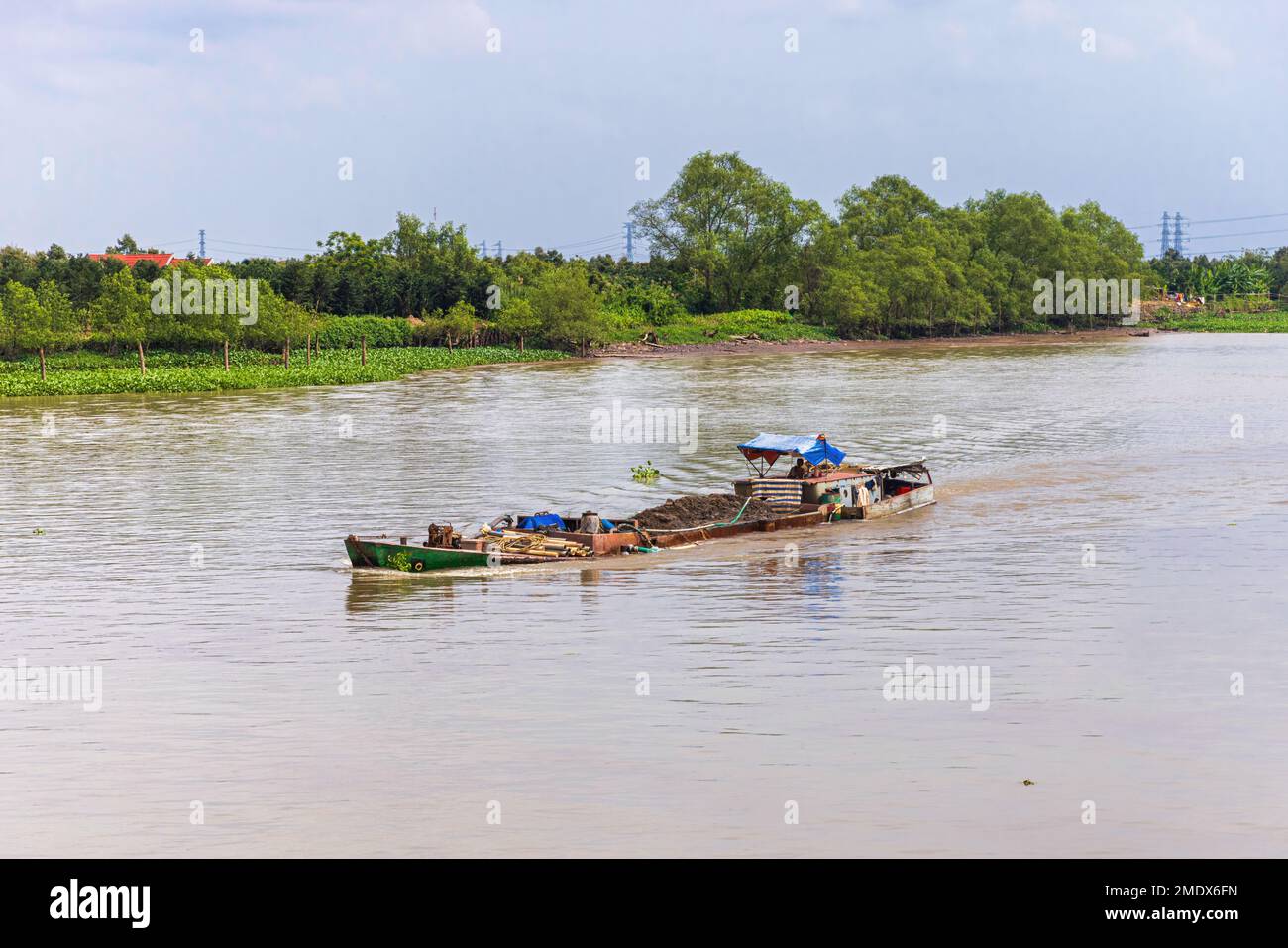 Heavy loaded cargo ship in the brown murky waters of the Mekong Delta ...
