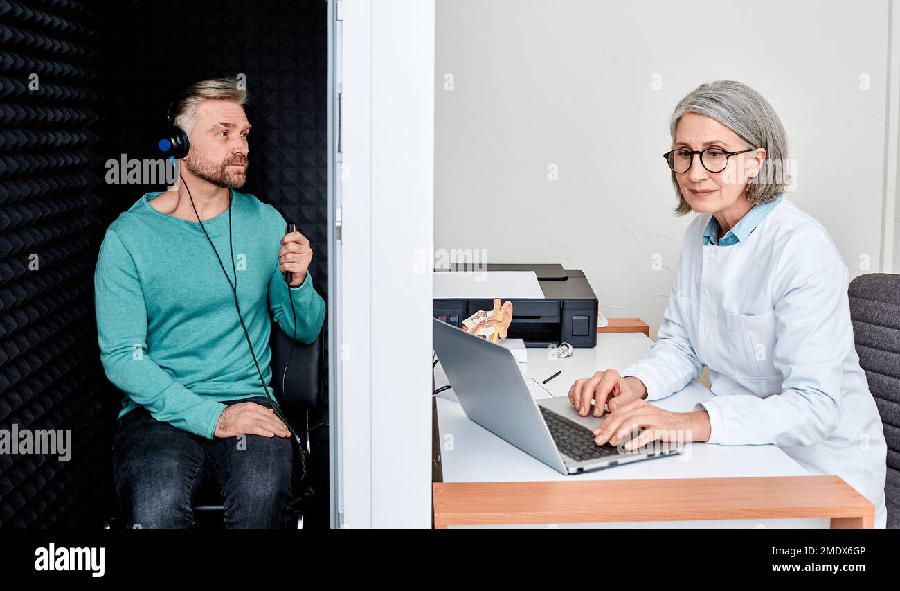 Audiological exam. Audiologist doing hearing check-up to handsome adult ...