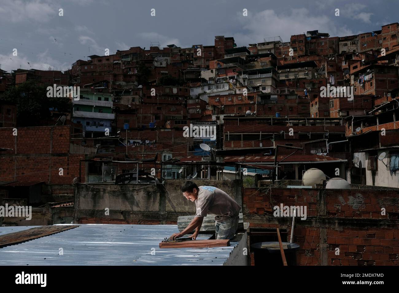 A man fixes the roof of his home in the Catia neighborhood of Caracas ...