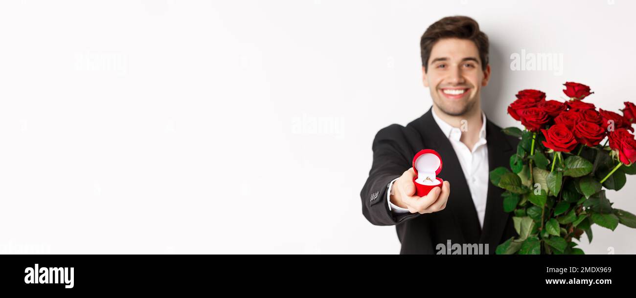Close-up of attractive man in suit, holding bouquet of roses giving an ...
