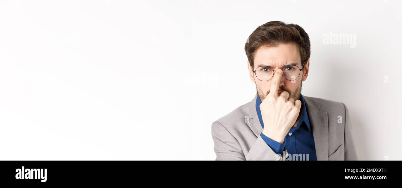 Serious boss in suit frowning, put on glasses and looking suspicious at ...