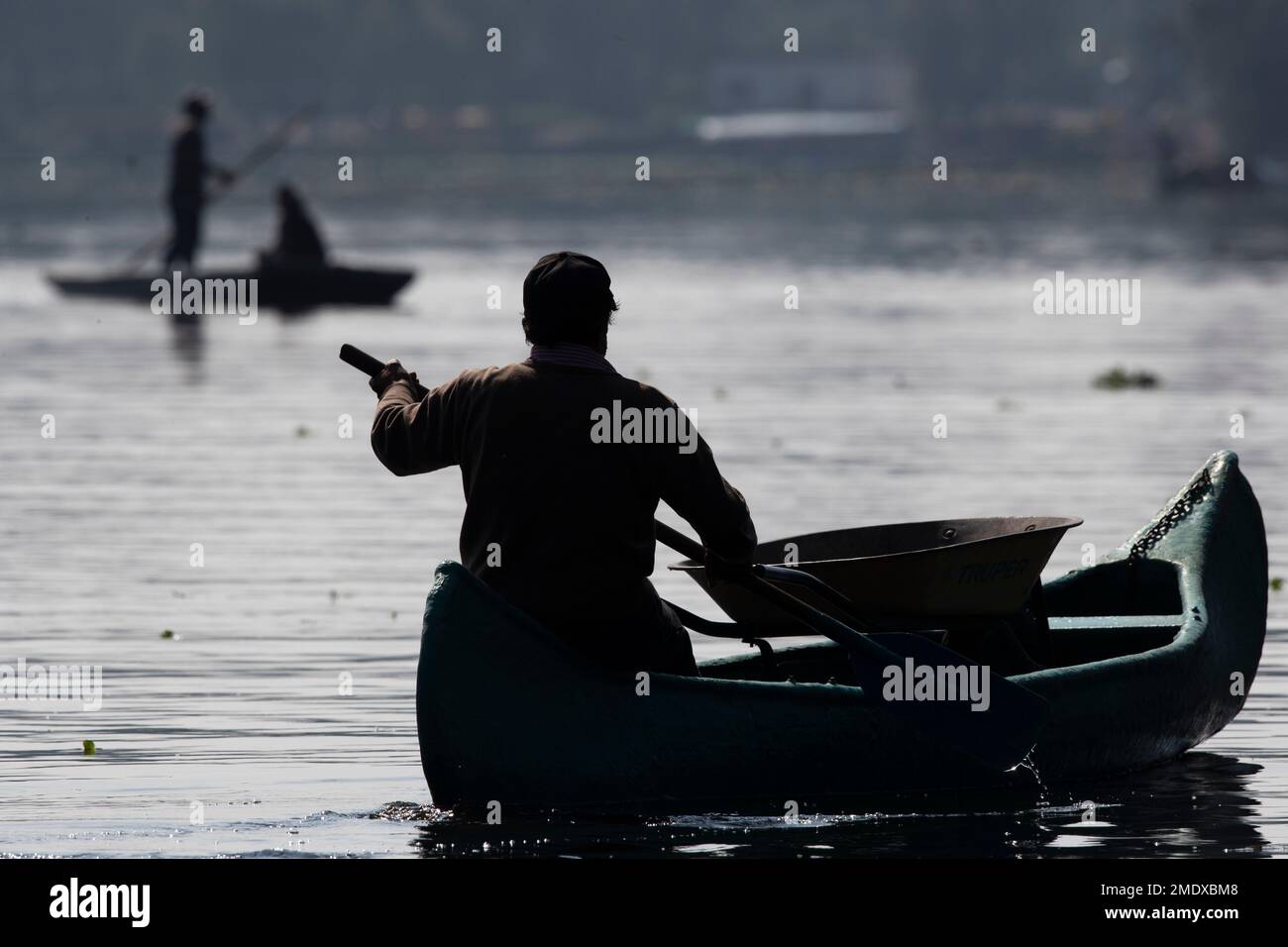A farmer carries a wheelbarrow in his canoe as e paddles to his farm ...