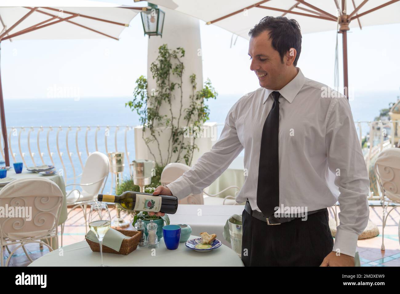 Waiter pouring wine at Michelin restaurant La Sponda at the luxury Le ...