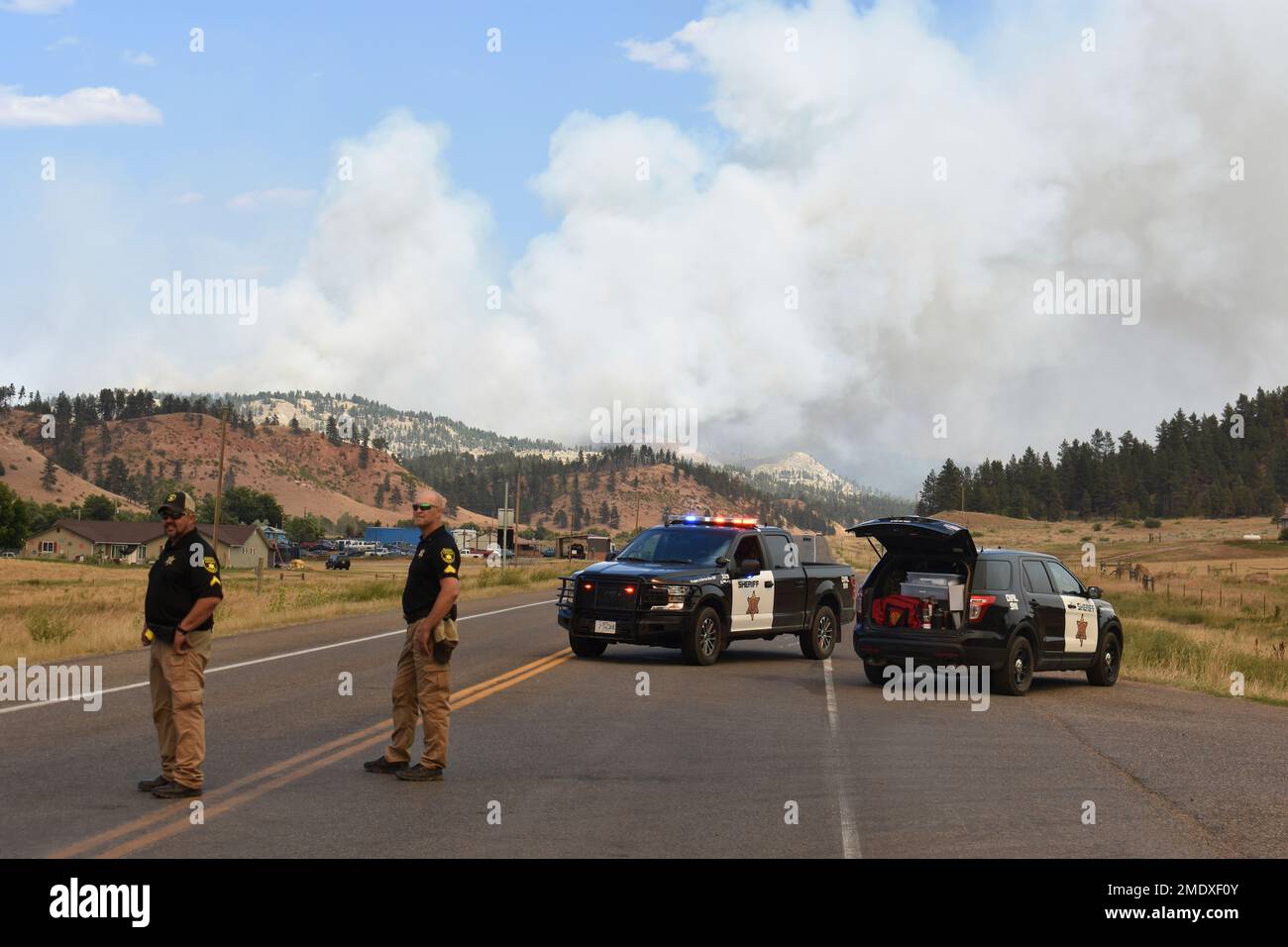 A plume of smoke rises from a wildfire as Cascade County sheriff's deputies prevent traffic from ...
