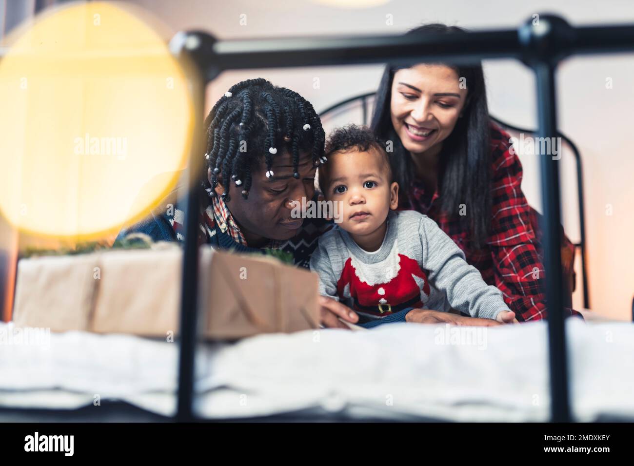 Toddler boy with his multiracial parents on a bed. High quality photo ...