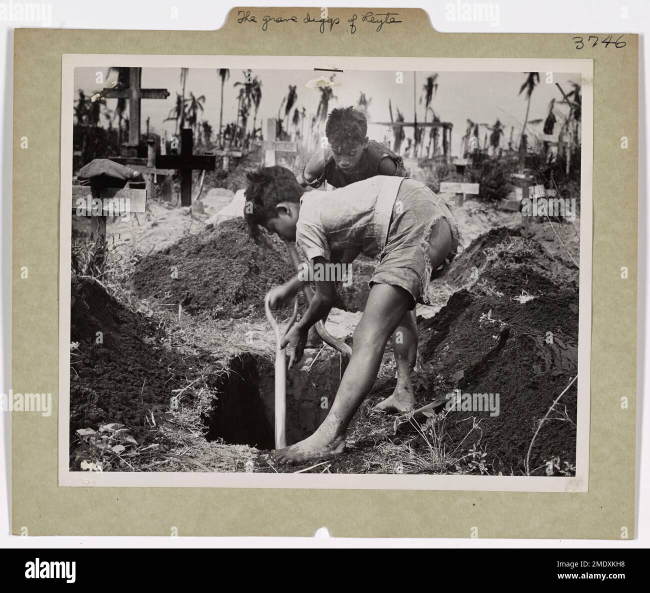 Two Filipino boys dig a grave in Leyte, Philippines, reflecting the ...