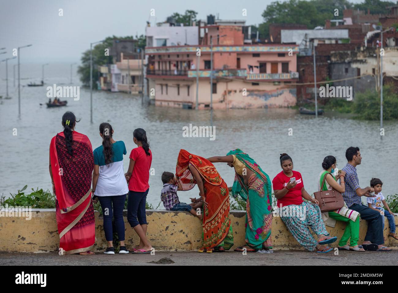 People stand on the banks of the overflowing river Ganges in Prayagraj ...
