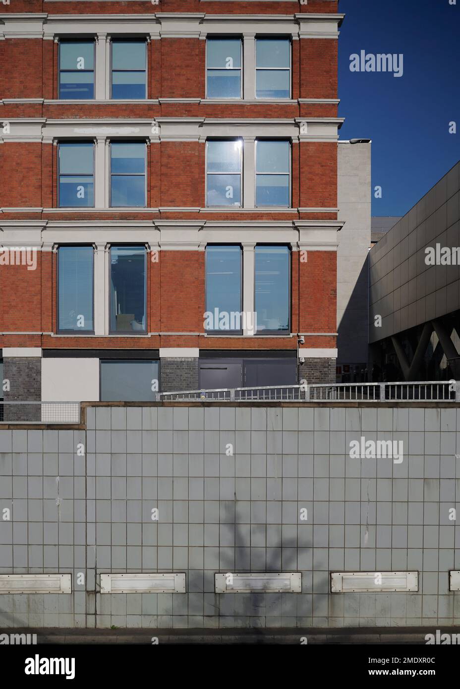Modern building with red brick above an old tiled wall Stock Photo - Alamy