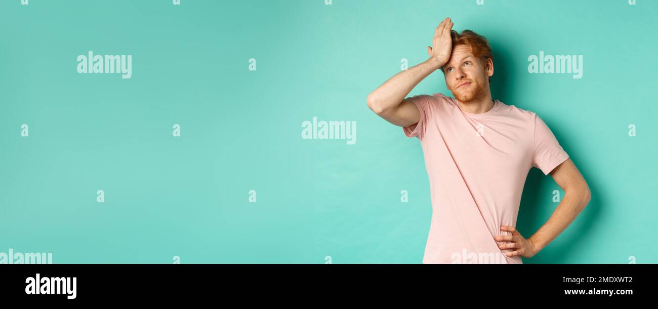 Annoyed and bothered redhead male model showing facepalm and roll eyes ...