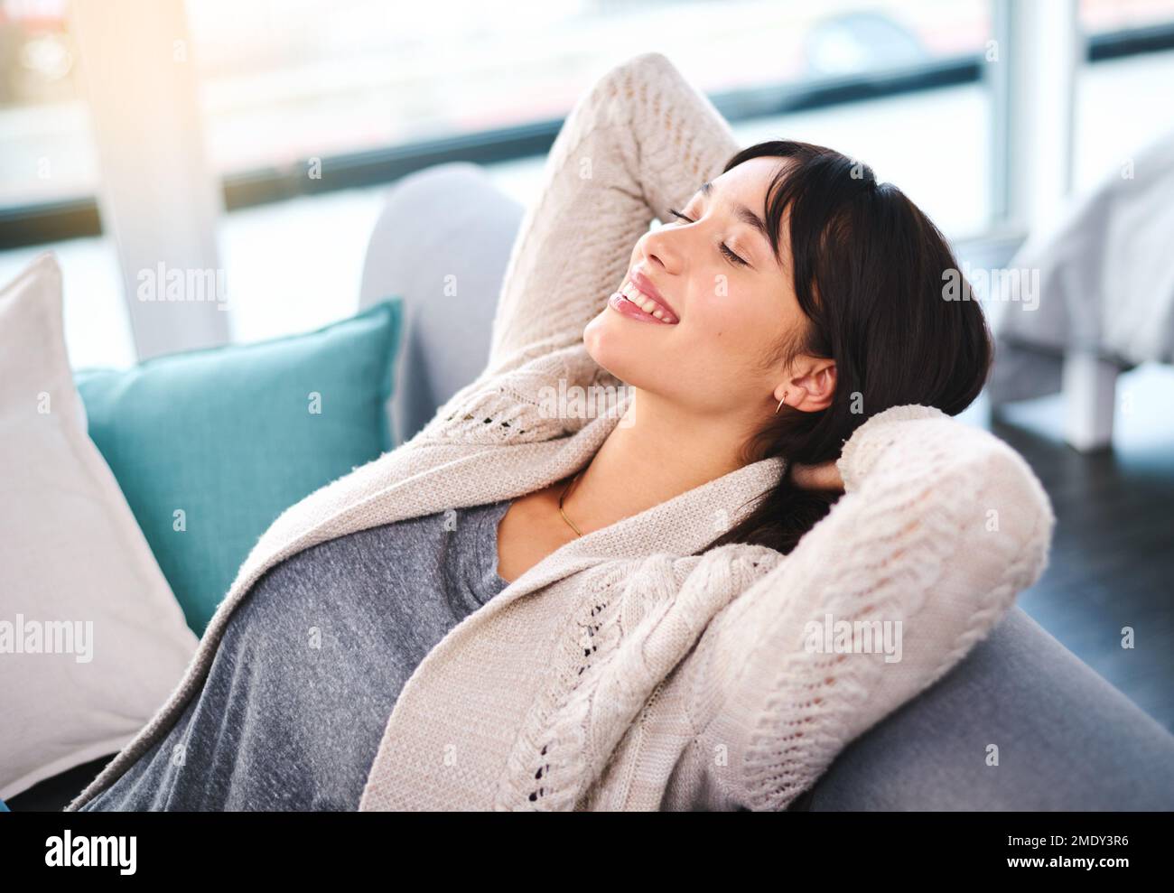 Relaxing like a champ. a relaxed young woman lying back on a sofa ...