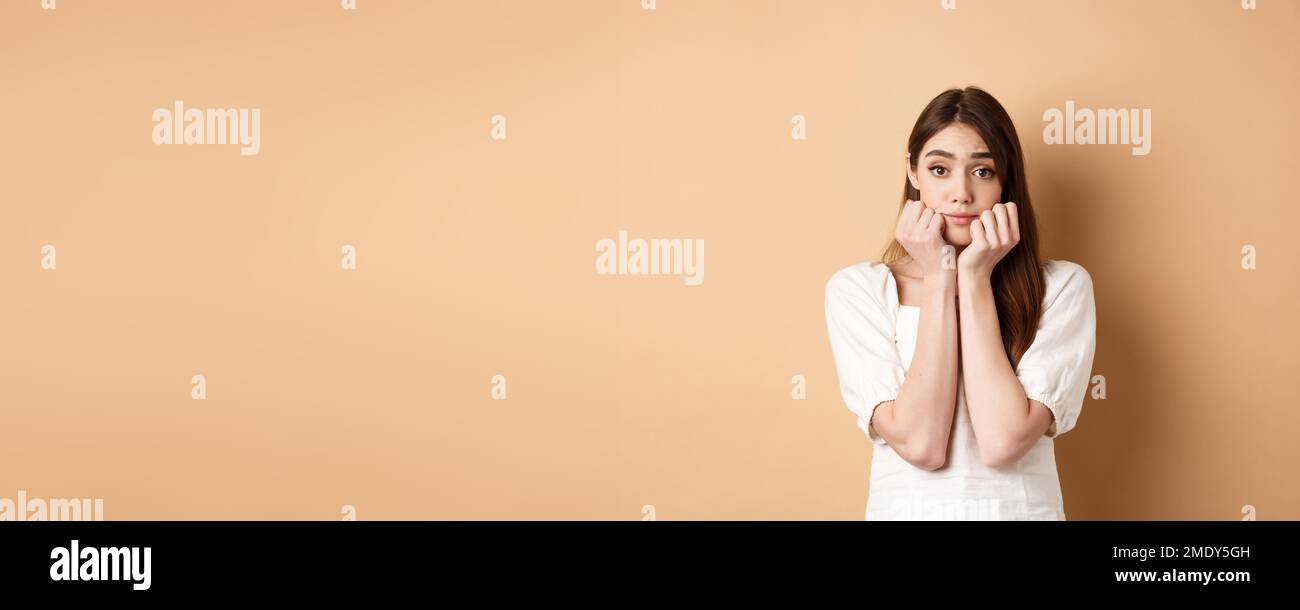 Cute and silly girl lean face on hands and looking dreamy at camera ...