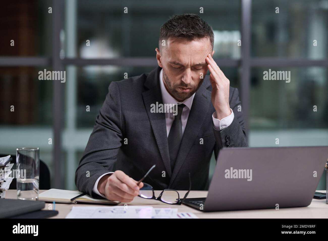 Stressed male director of business corporation touching head by hand ...