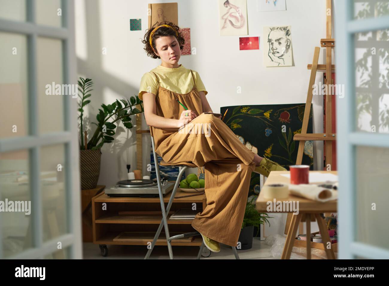 Young inspired female artist making sketches of painting subjects in ...