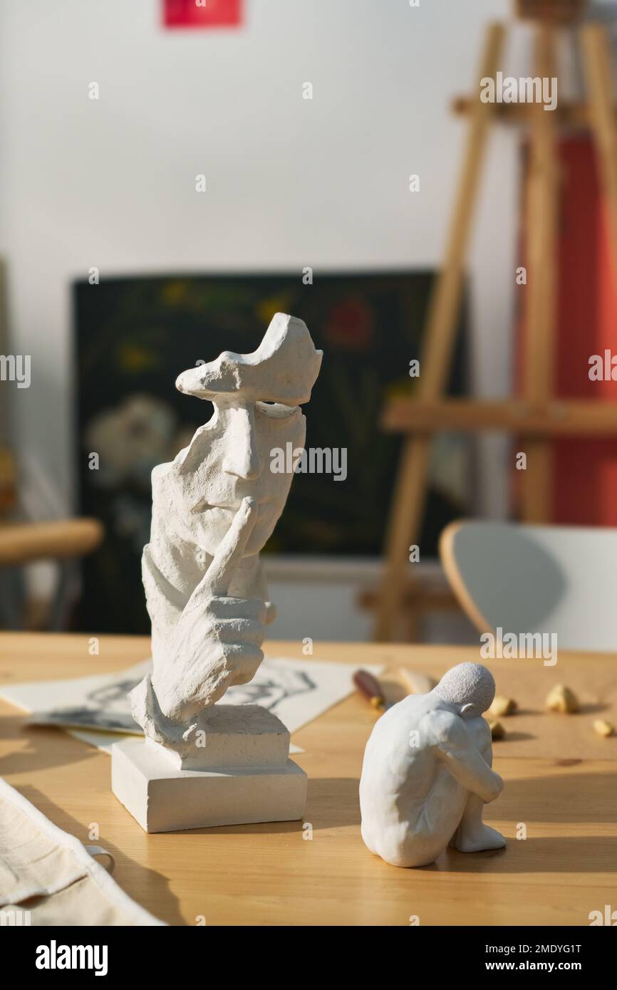 Two small handmade clay or gypsum figurines on wooden table in craft ...