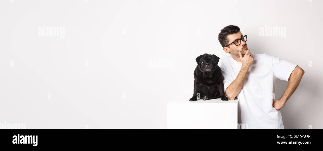 Image of handsome young man, pet owner standing with his dog and ...