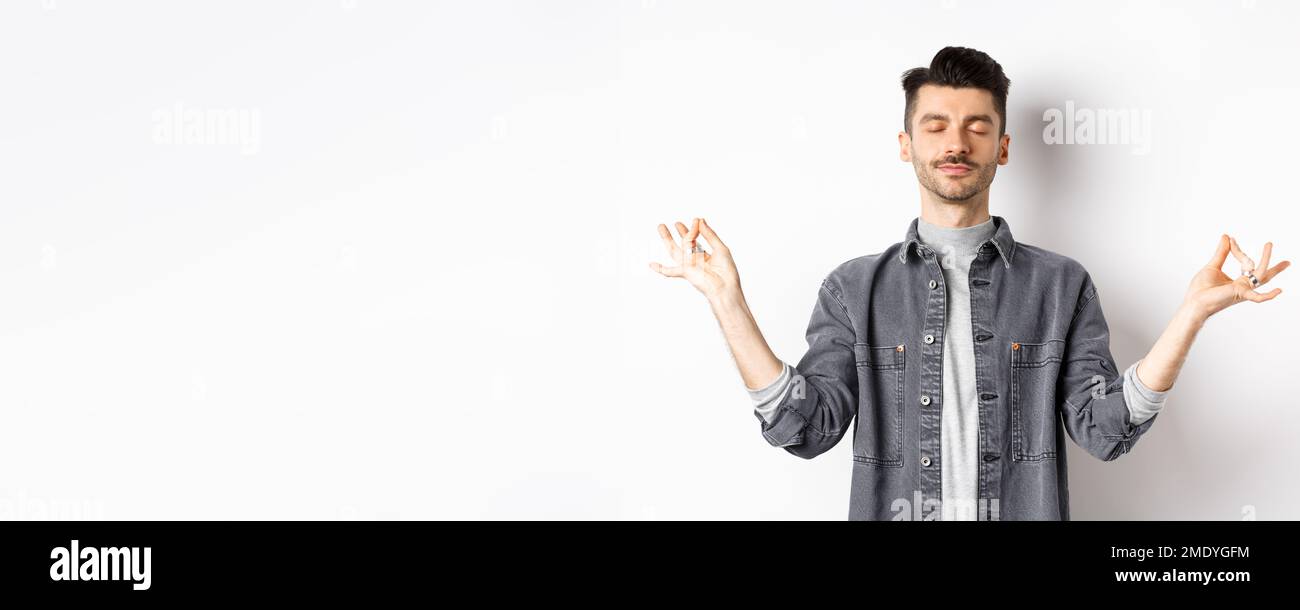 Calm guy meditating with peaceful face, holding hands in zen mudra sign ...