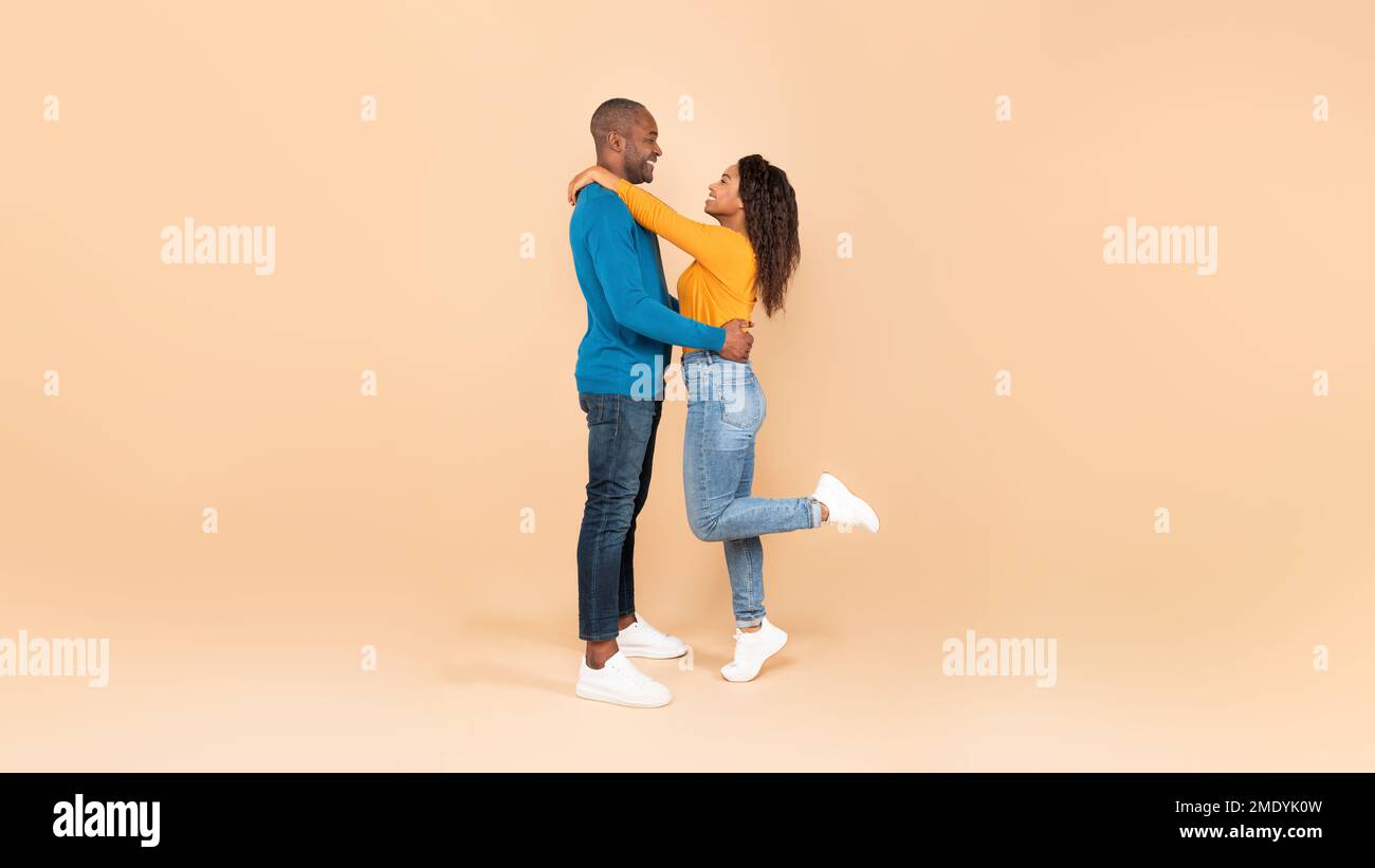 Couple in love. African american spouses hugging, standing over peach ...