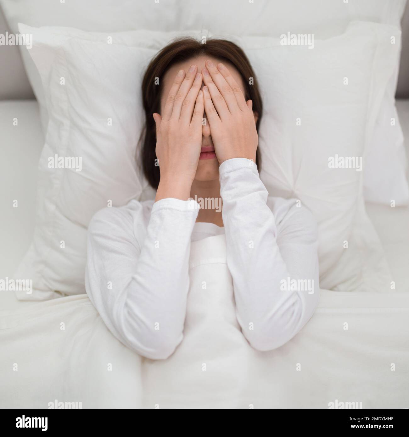 Top view of unhappy brunette woman lying in bed Stock Photo - Alamy