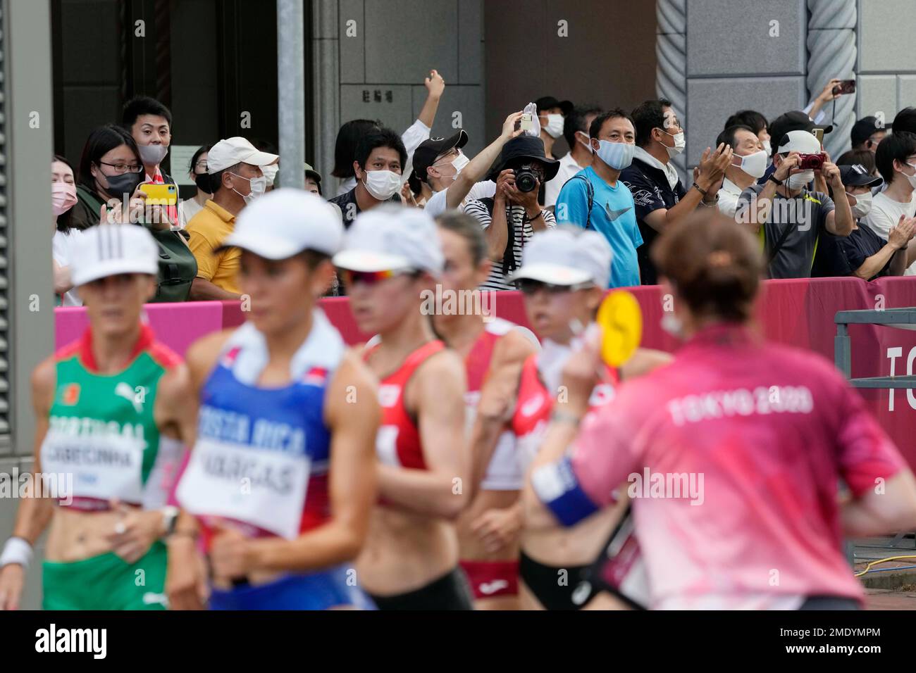 Spectators watch as competitors compete in the women's 20km race walk ...