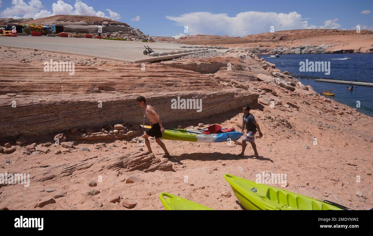 Visitors carry a kayak up a newly exposed cliff face beneath the closed ...