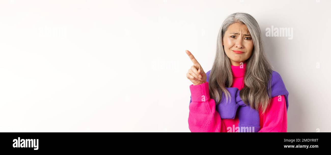 Judgy and skeptical asian senior woman grimacing displeased, pointing ...