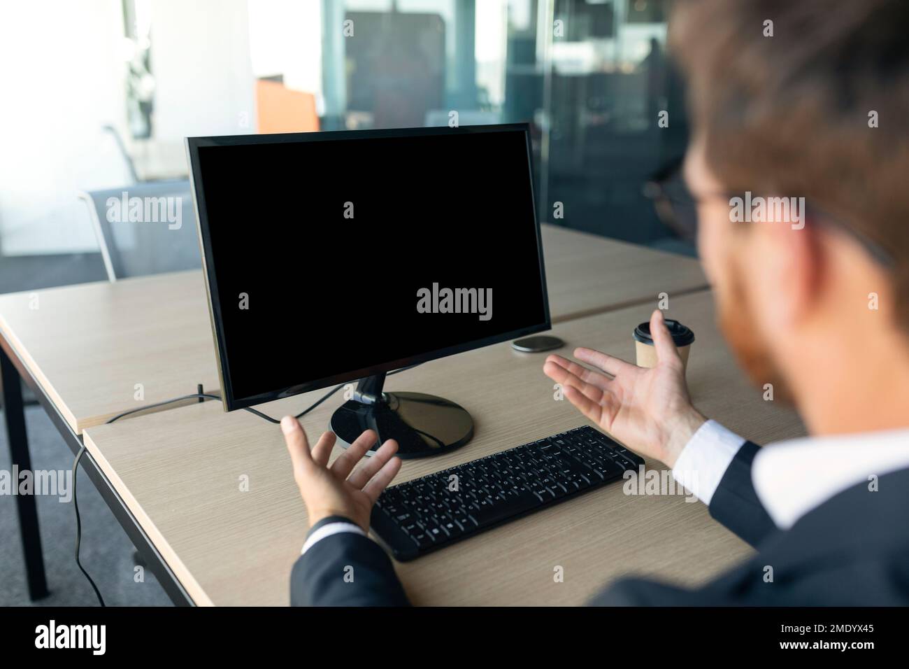 Male entrepreneur gesturing at computer webcamera, monitor with blank ...