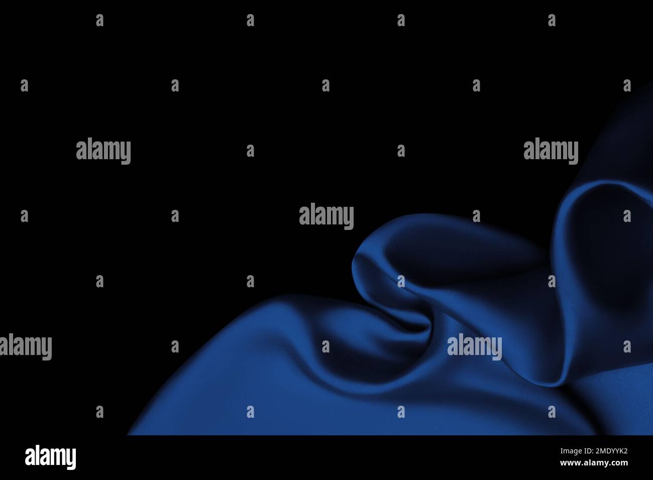 Blue satin fabric lays on the surface in the form of openwork folds ...