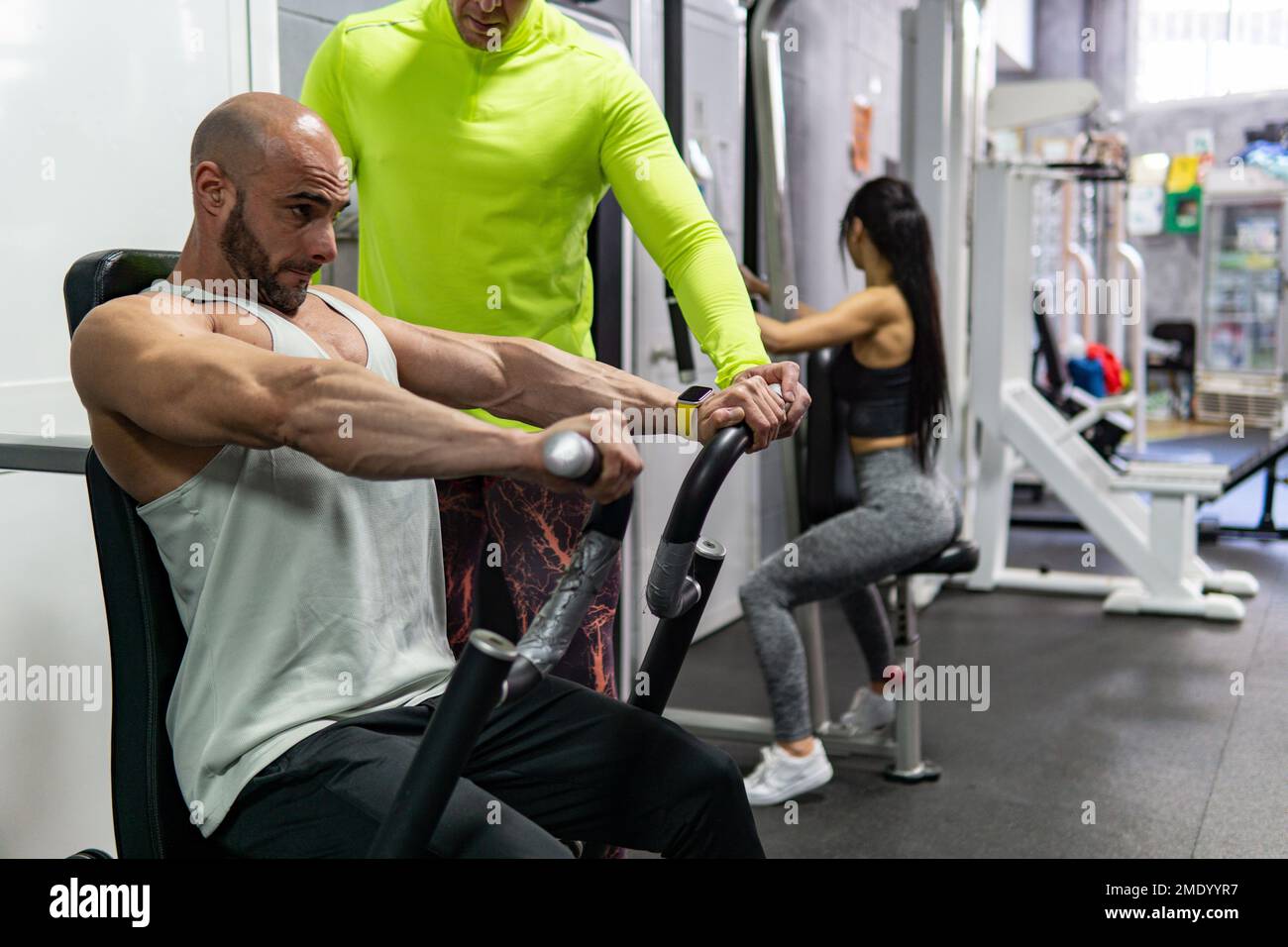 Gym trainer who helps the athlete to use the weight machine in the gym ...