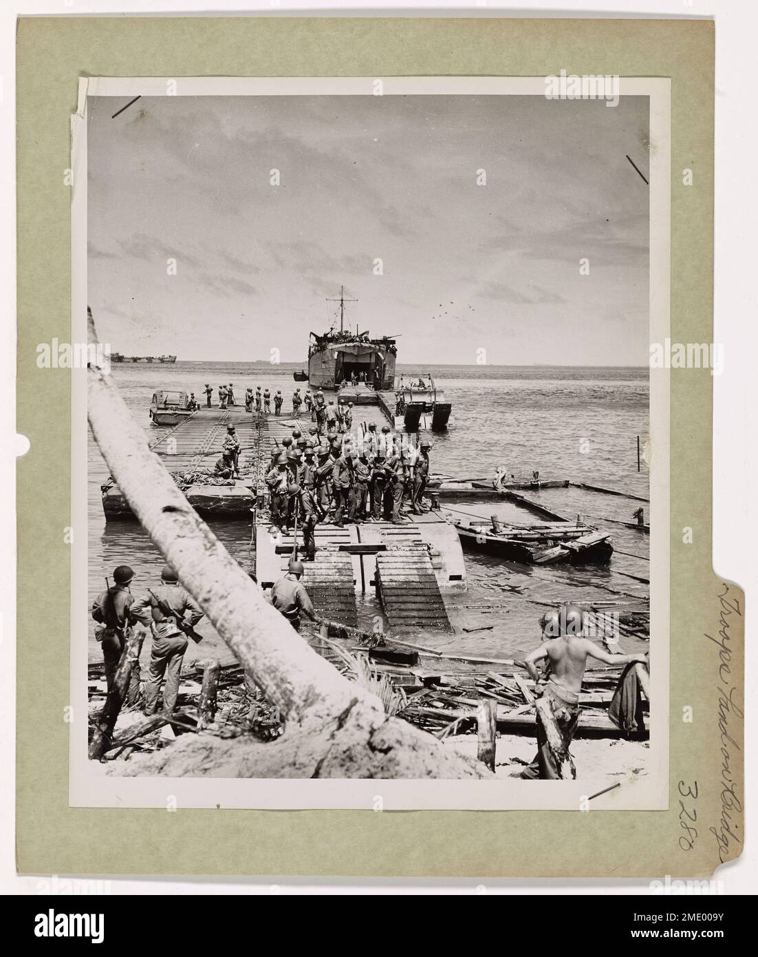 A Coast Guard-manned LST tows a sectional pontoon bridge into position ...