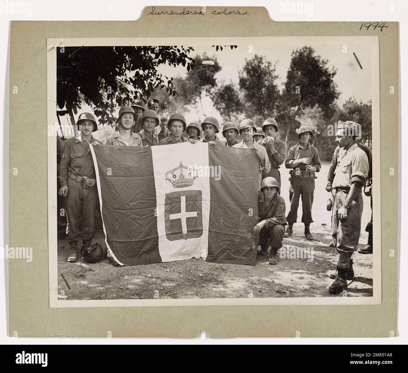 U.S. soldiers stand with an Italian flag surrendered by Axis forces ...