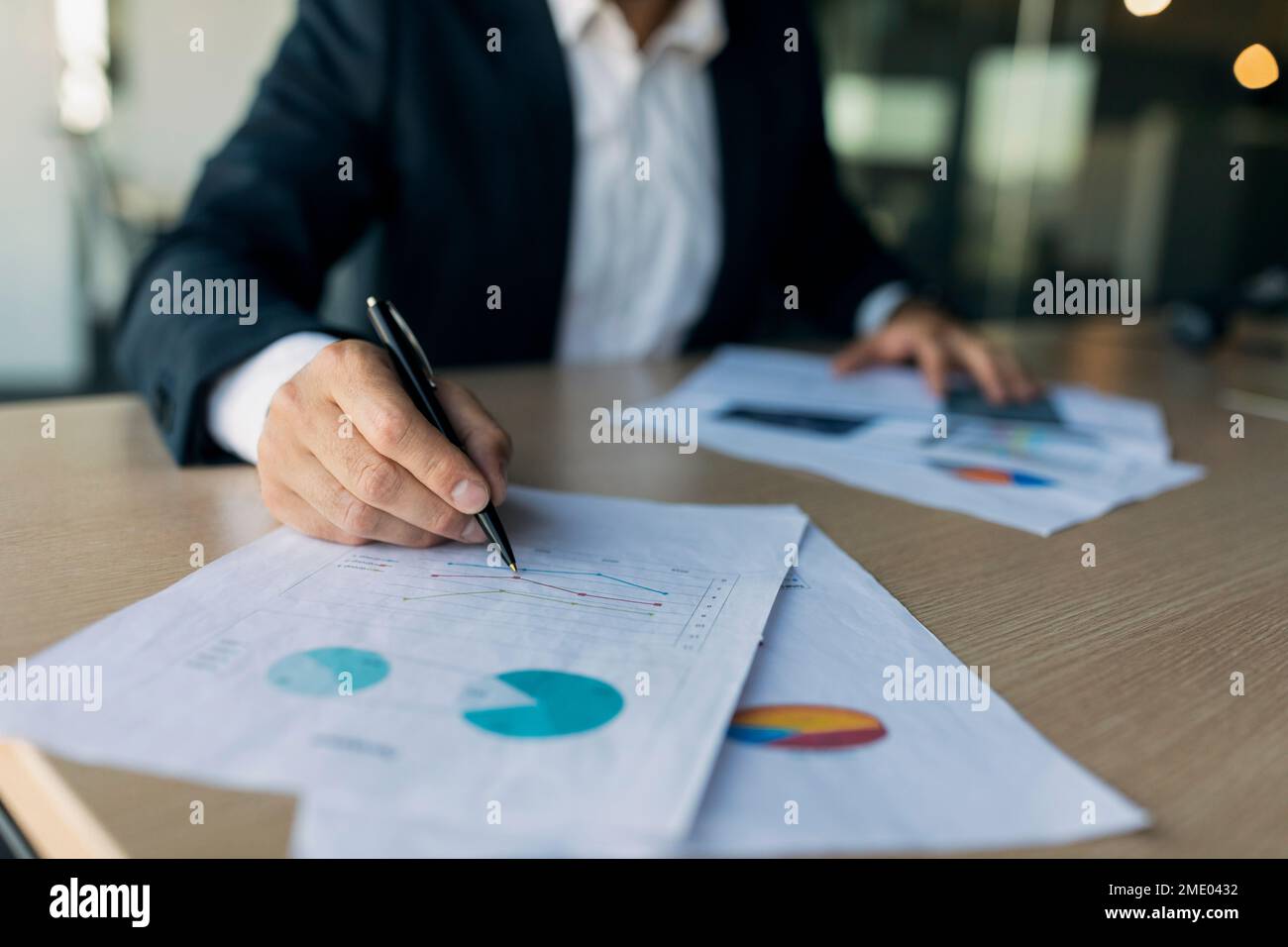 Male business analyst writing on papers, checking data, charts and graphs, sitting at desk in ...