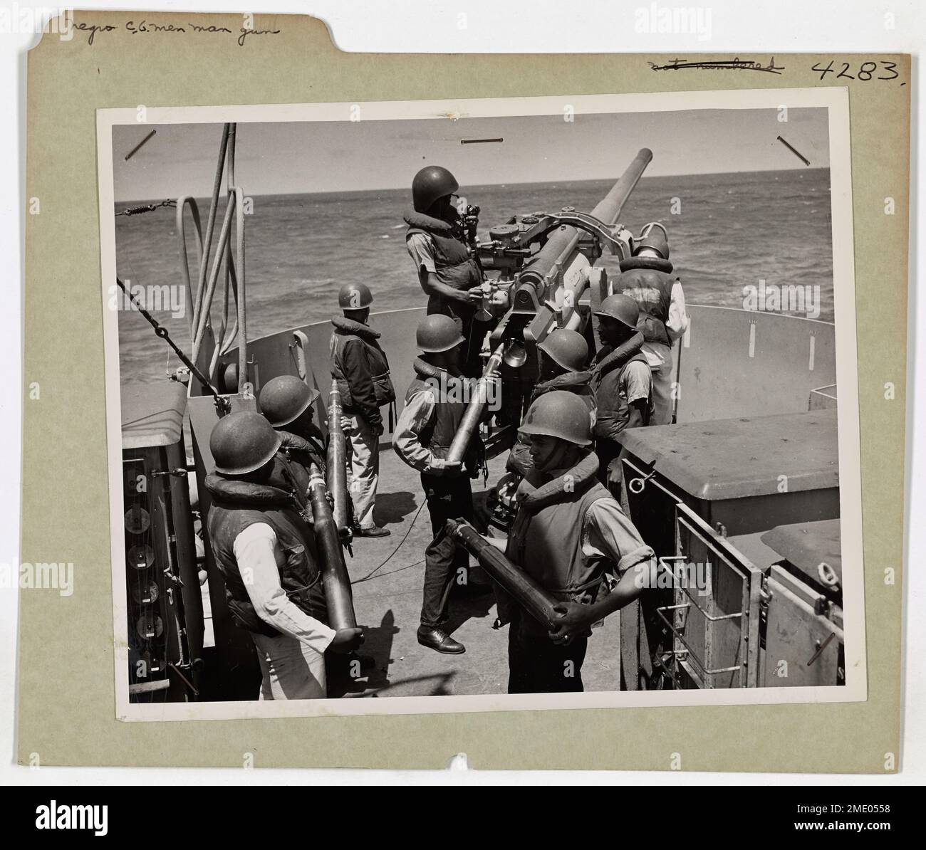 A group of African American Coast Guardsmen stand beside a three-inch ...