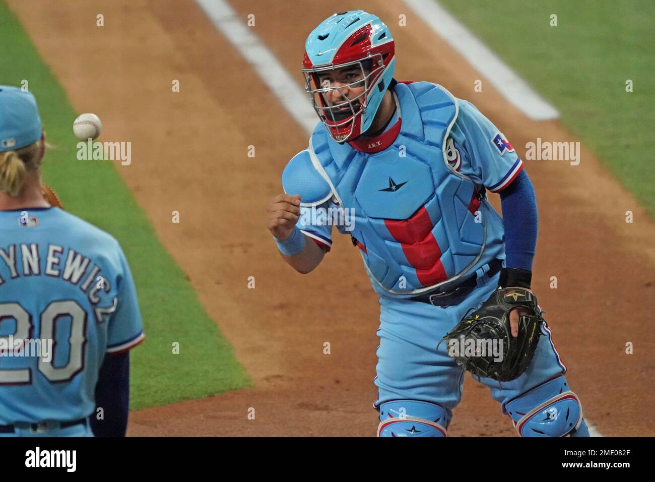 Texas Rangers catcher Jose Trevino flips the ball to the pitcher ...