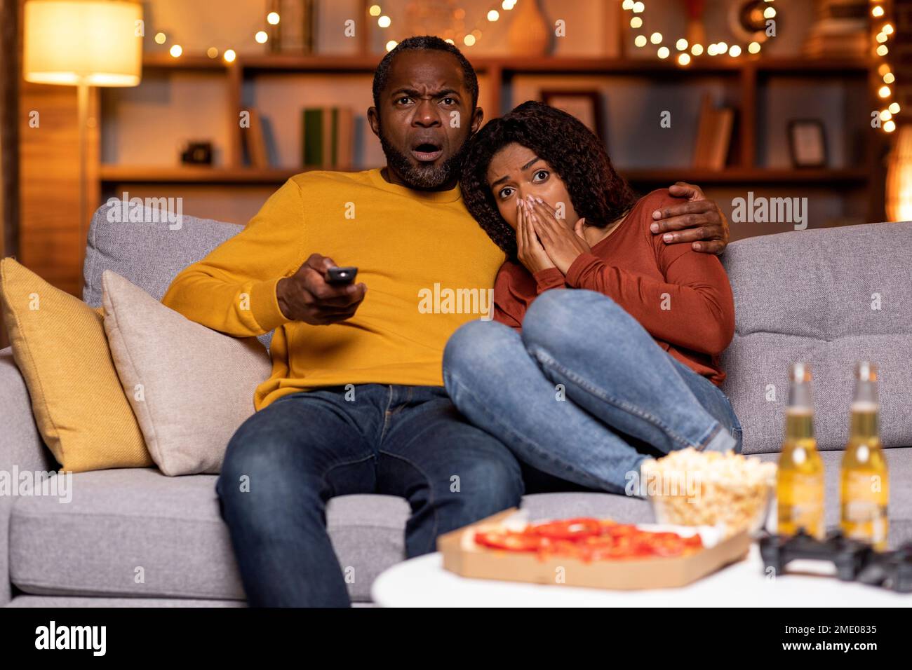 Frightend black couple watching horror movie at home Stock Photo - Alamy