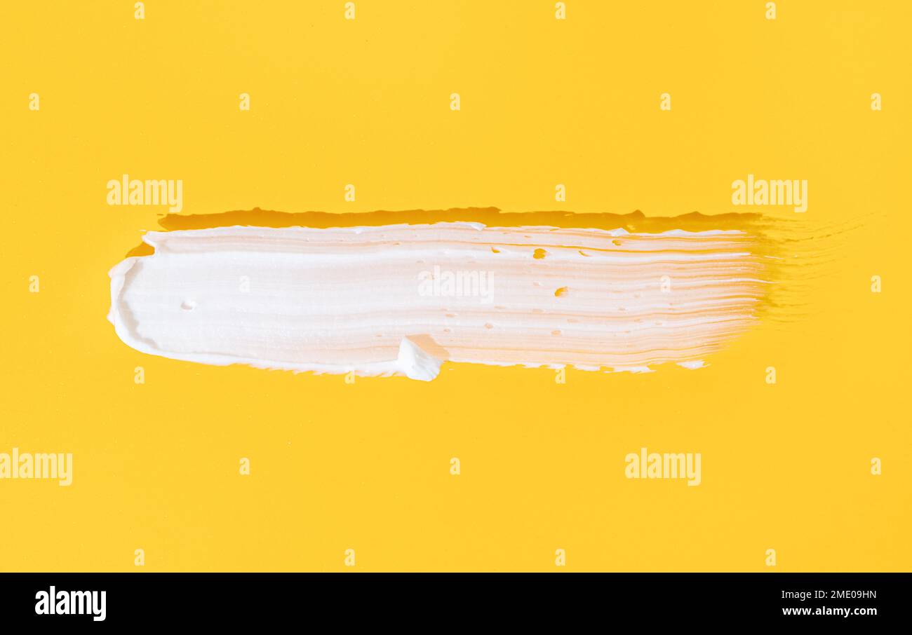 White Cosmetic cream smear isolated on yellow background. Skin care ...