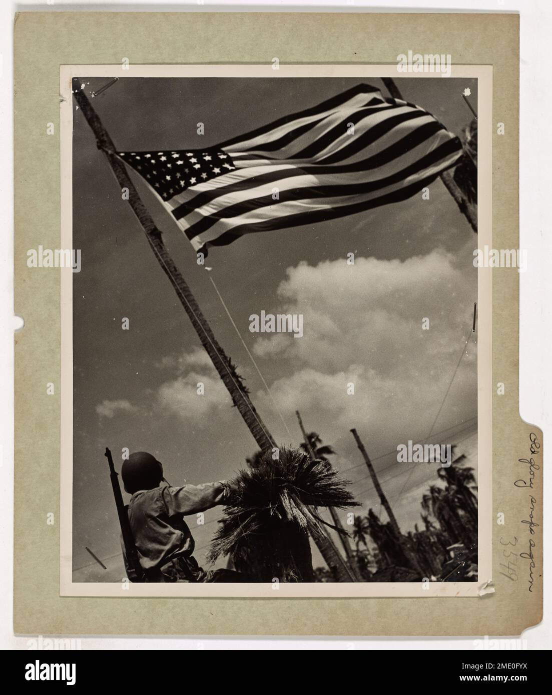 Coast Guardsman Frank L. Cuenca stands beside the American flag on ...