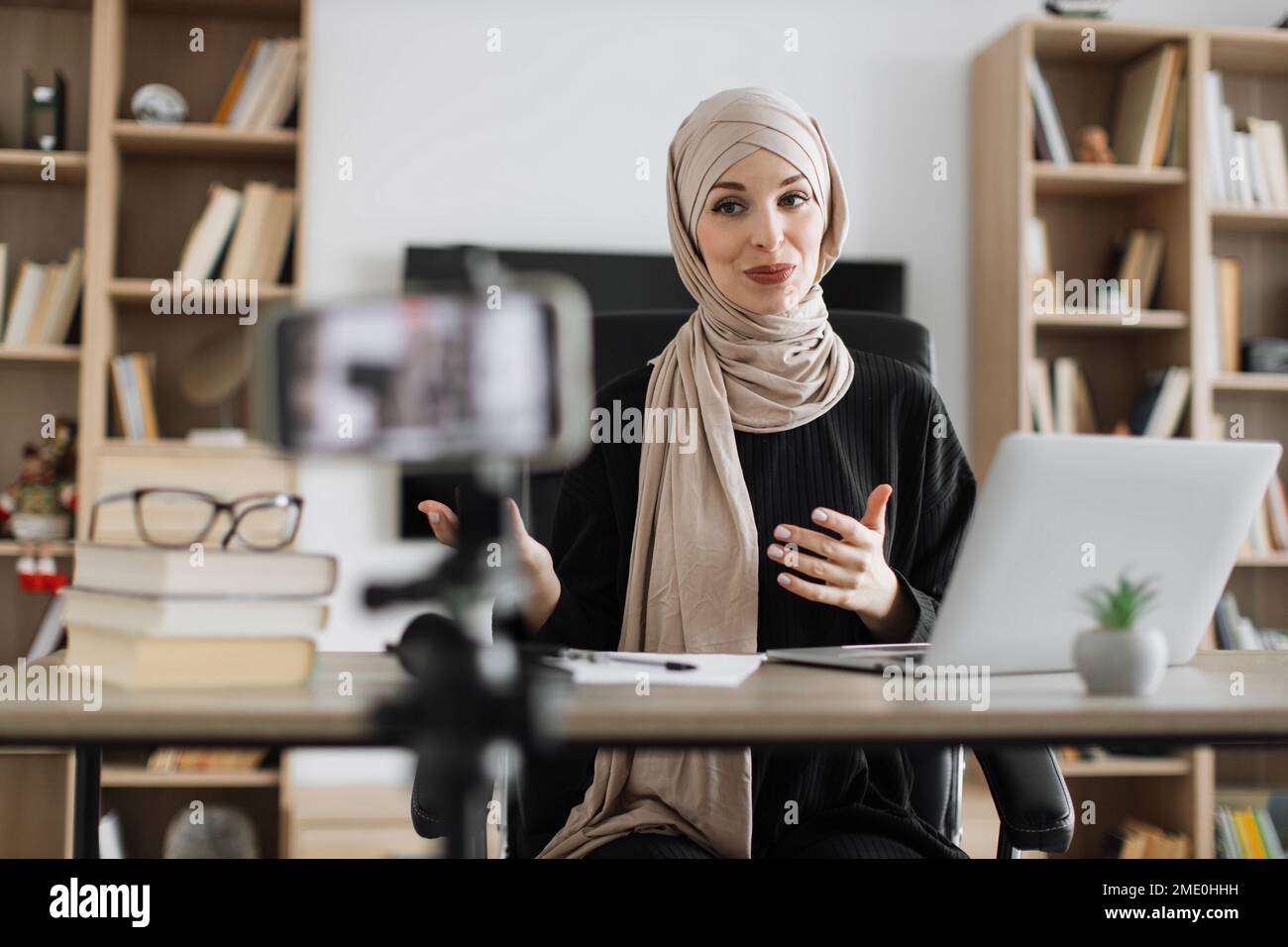 Charming muslim woman in hijab talking and gesturing while recording ...