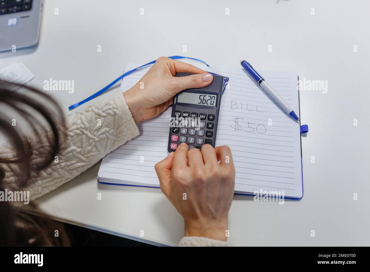 upper view on woman hands counting expences on calculator at her desk ...