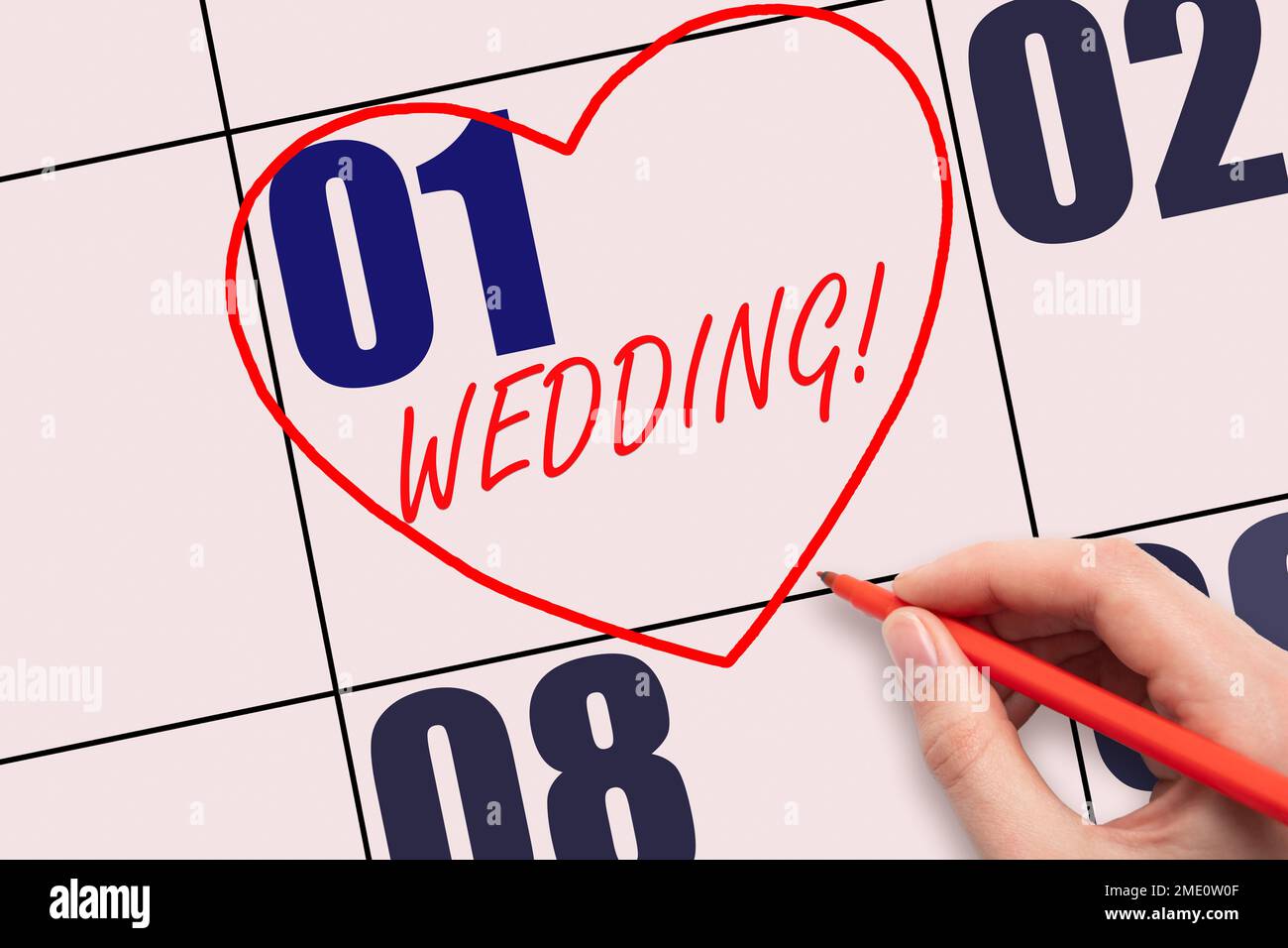 1st day of the month. Hand writing text WEDDING and drawing a red heart ...