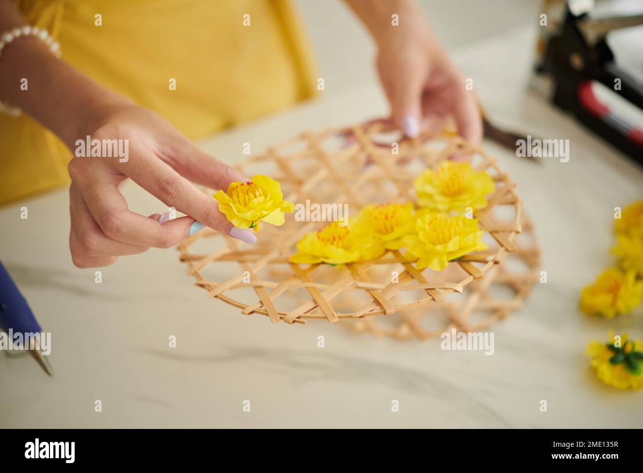 Hands of creative woman making Tet decorations with artificial yellow ...