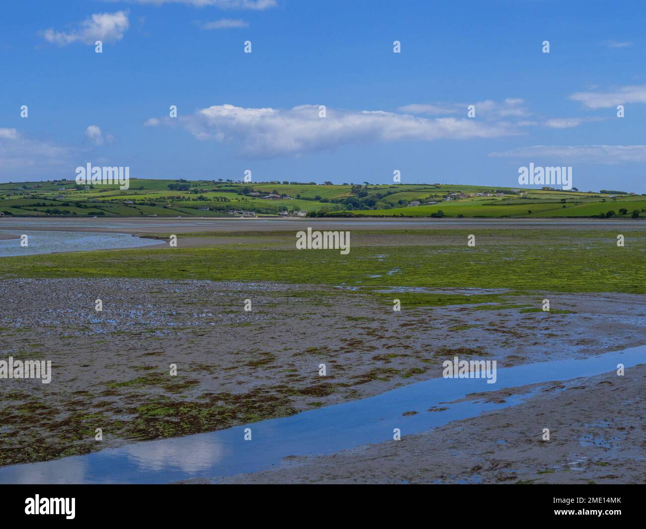 Open seabed after low tide, swamp. Green hilly landscape. White clouds in a sky. Irish landscape ...