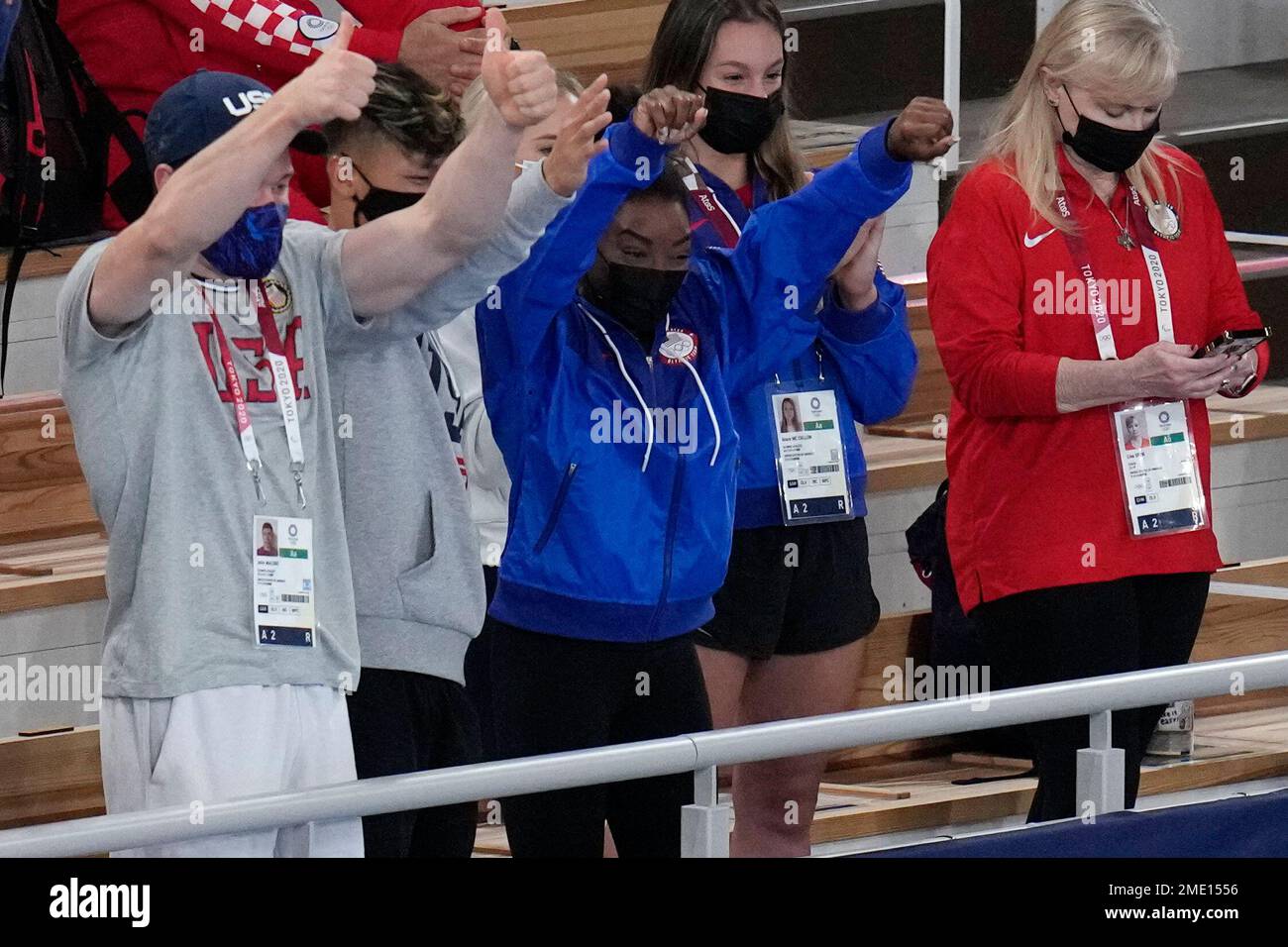 Simone Biles, of the United States, center in blue, reacts alongside ...