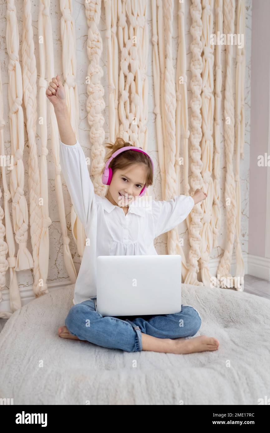 Caucasian funny child kid in headphones, sitting with computer, laptop ...